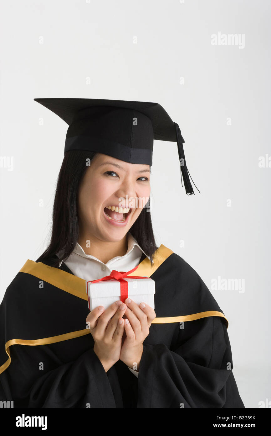 Portrait of a young female graduate holding a gift and laughing Stock ...