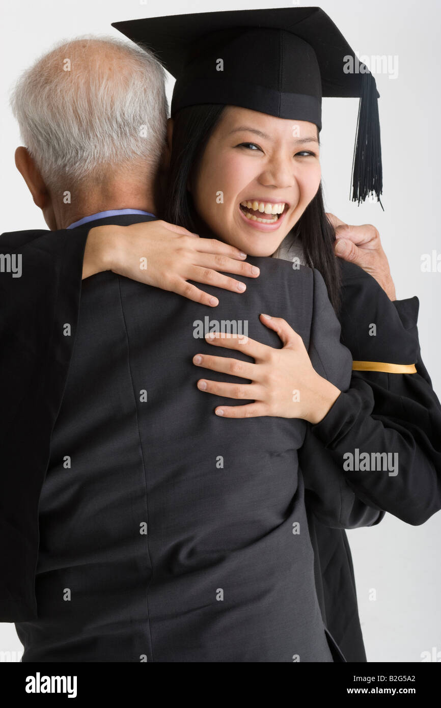 Portrait of a young female graduate hugging her father and laughing ...