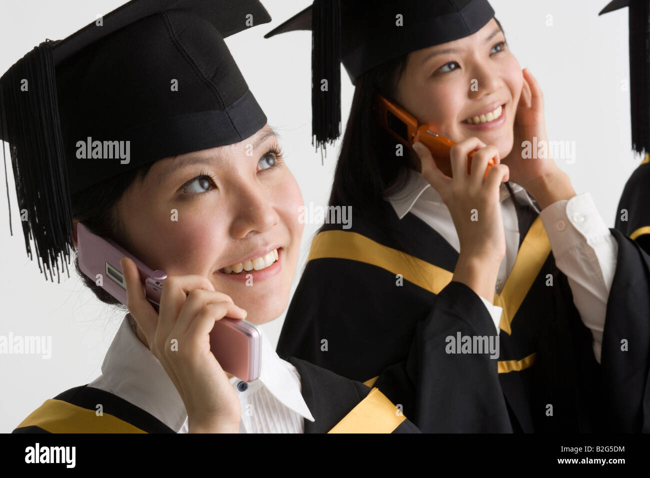 Two female graduate students talking on mobile phones and smiling Stock ...