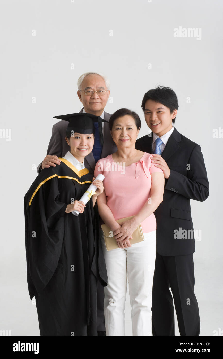 Portrait of a young female graduate standing with her family and ...