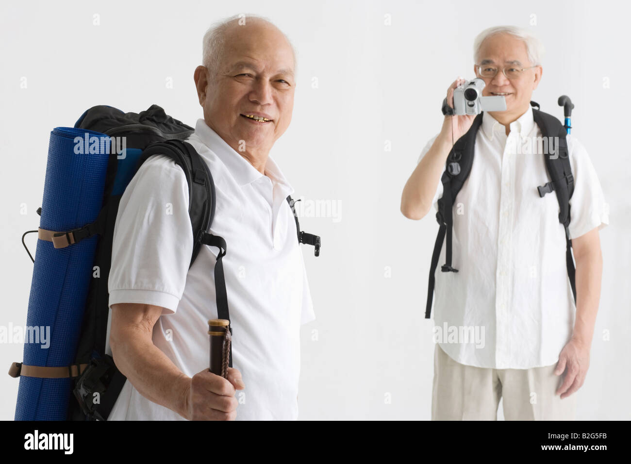 Portrait of a senior man smiling and his friend filming in the ...