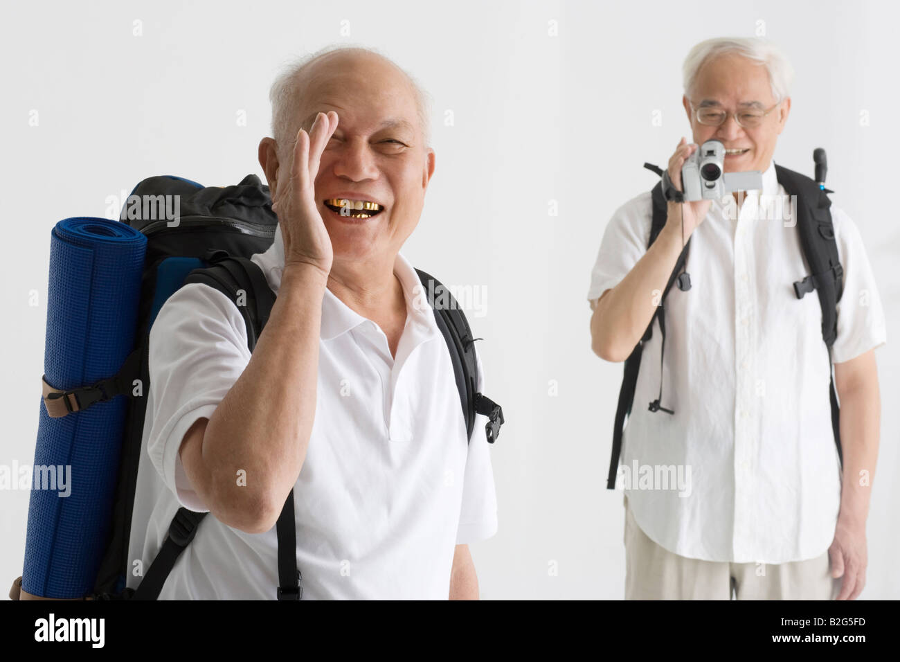Portrait of a senior man smiling and his friend filming in the ...