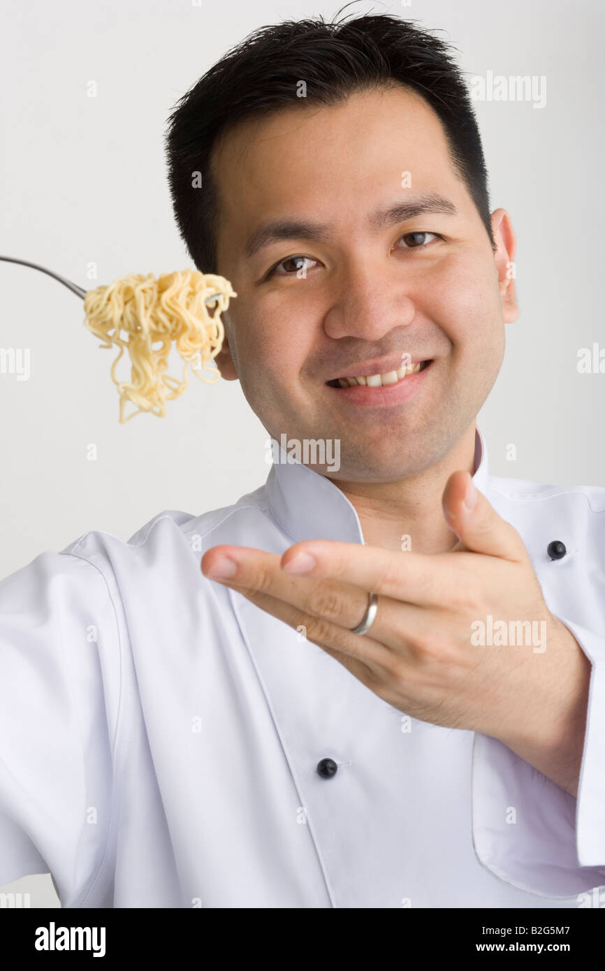 Portrait of a male chef tasting noodles and smiling Stock Photo - Alamy