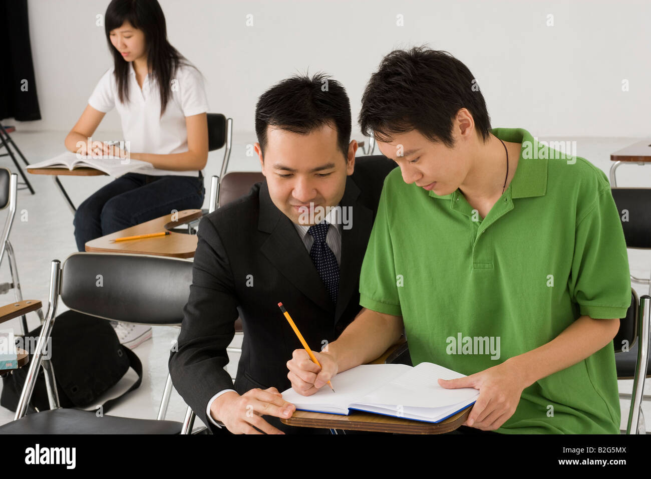 Professor helping a student in a classroom Stock Photo - Alamy