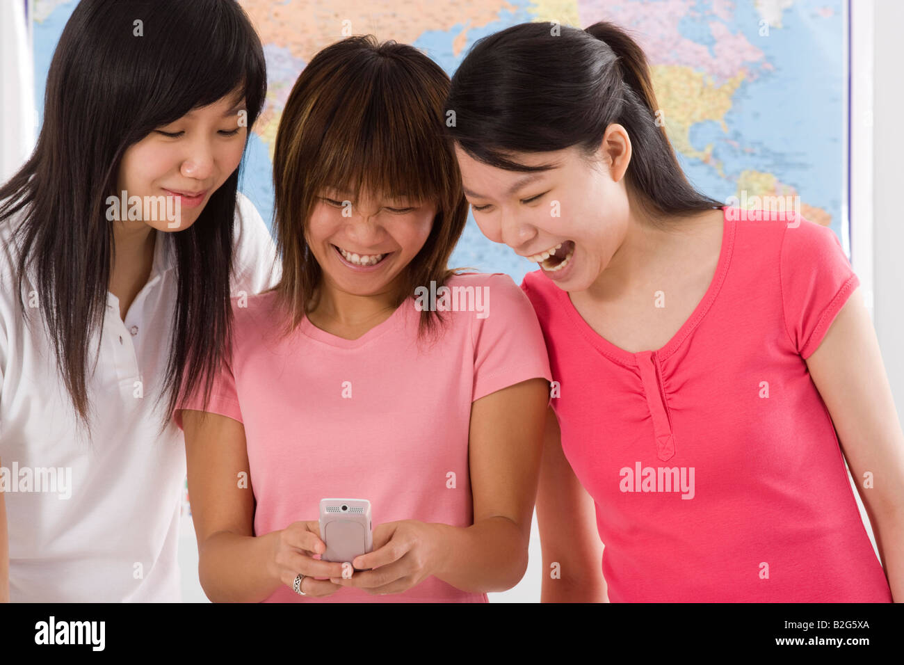 Three young women text messaging and smiling Stock Photo - Alamy