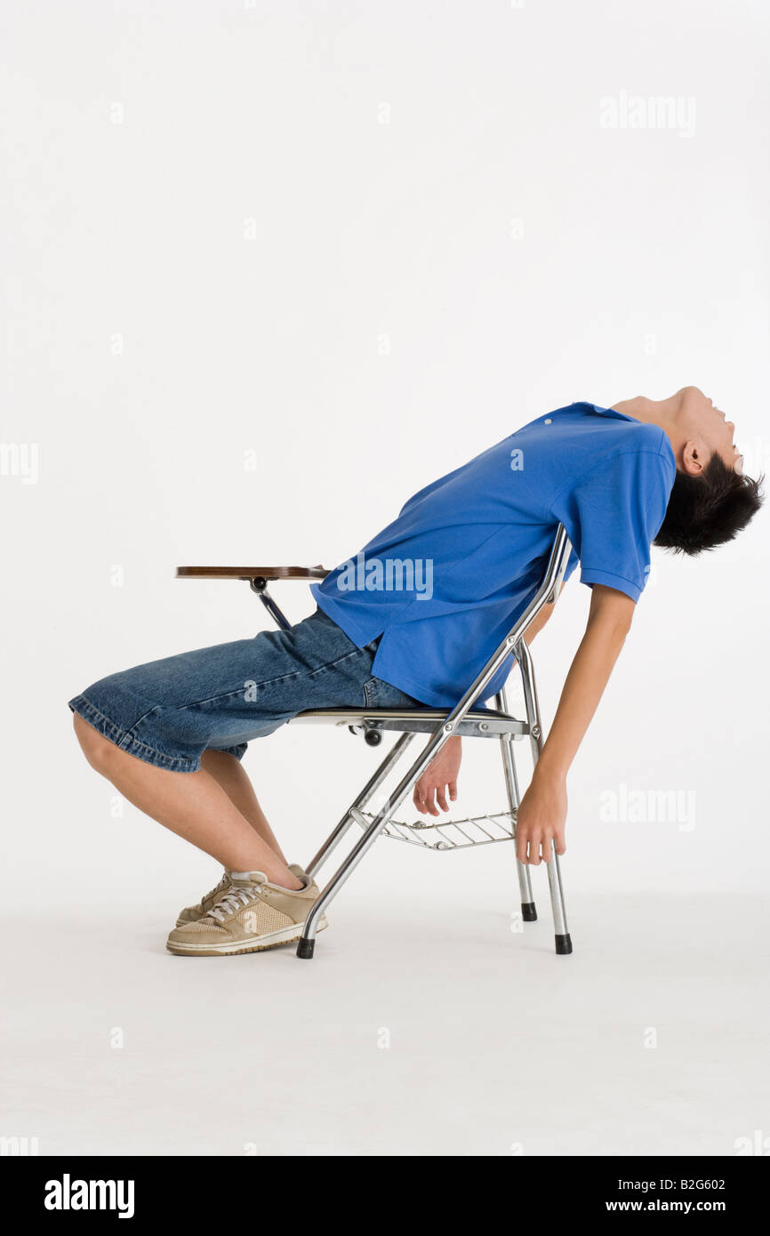 Young man napping on a writing chair Stock Photo - Alamy