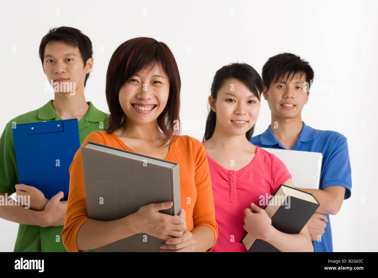 Portrait of four university students standing and smiling together ...