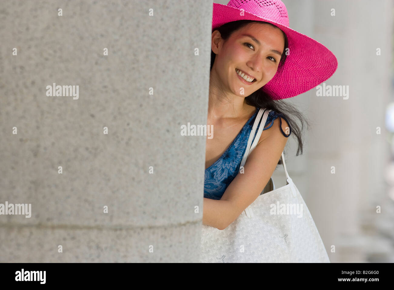 Portrait of a young woman hiding behind a column and smiling Stock ...