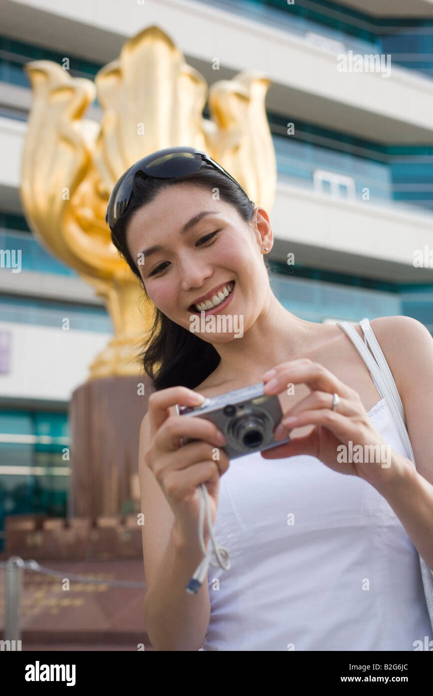 Young woman photographing with a digital camera and smiling Stock Photo ...