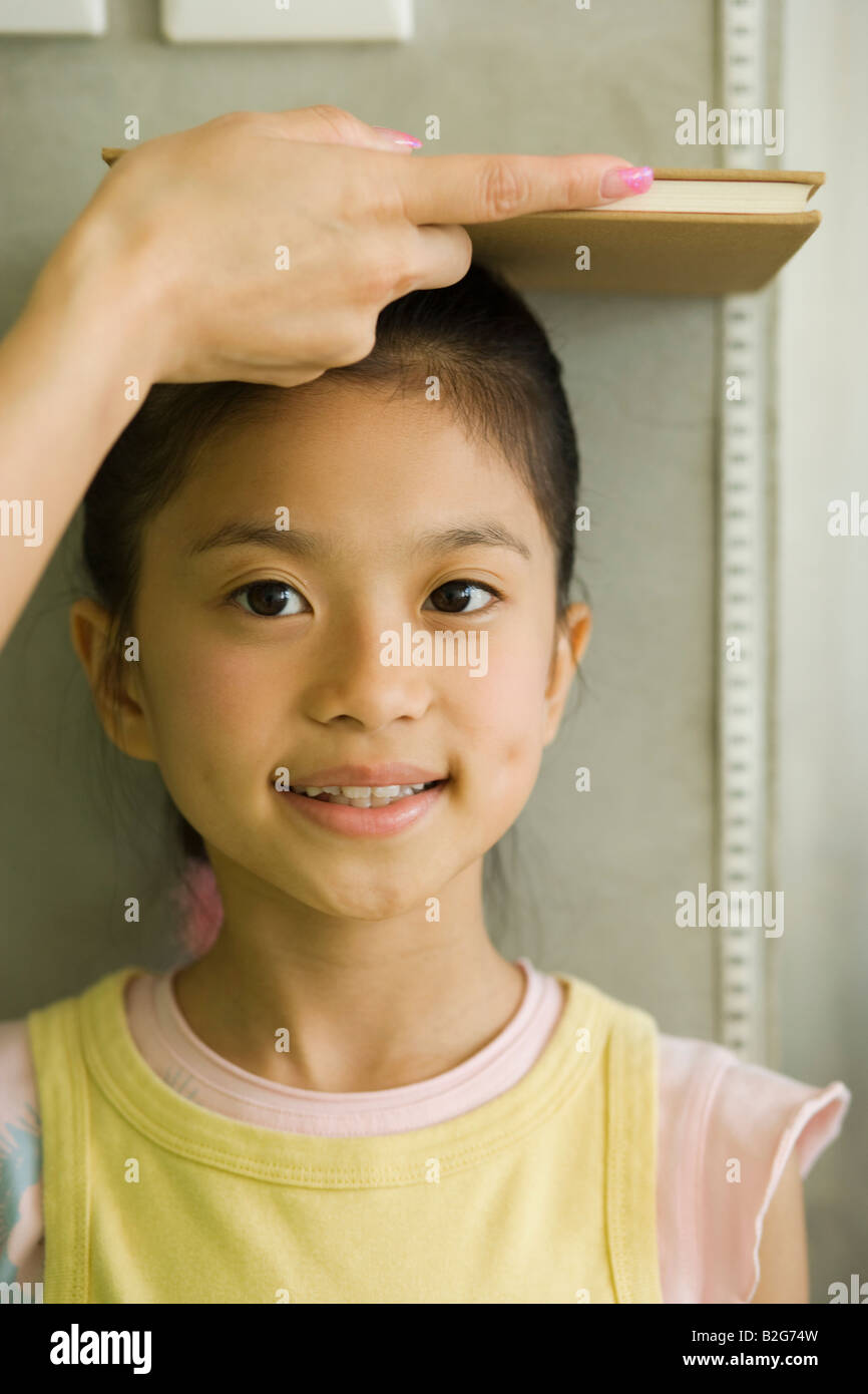 Woman measuring girl's height against a wall Stock Photo - Alamy