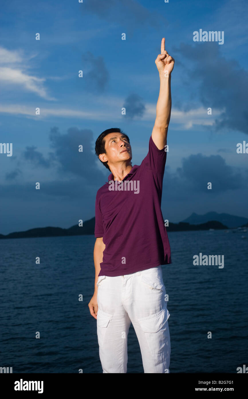 Mid adult man pointing upwards on the beach Stock Photo - Alamy