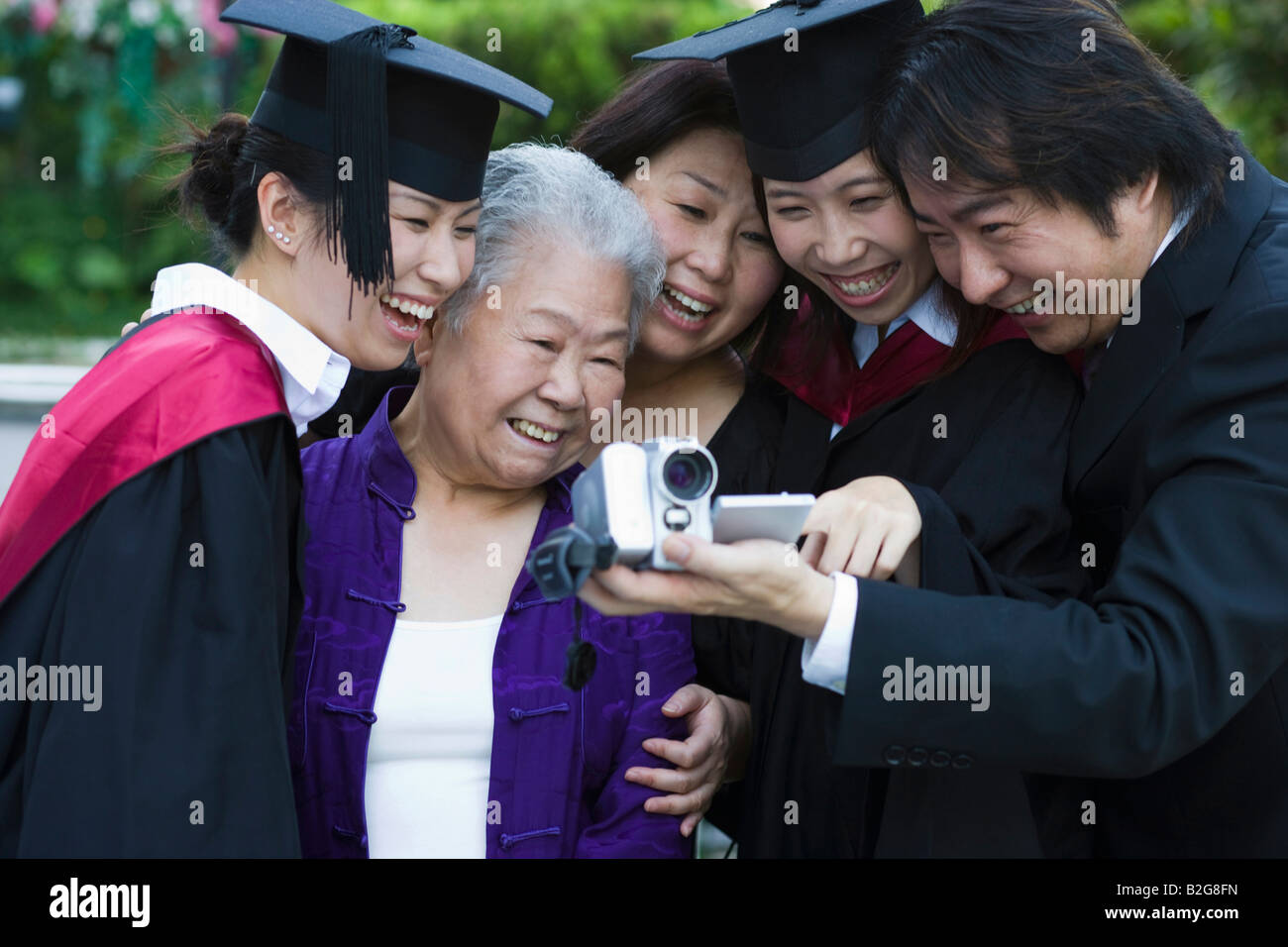 Family looking at a home video camera and smiling Stock Photo - Alamy
