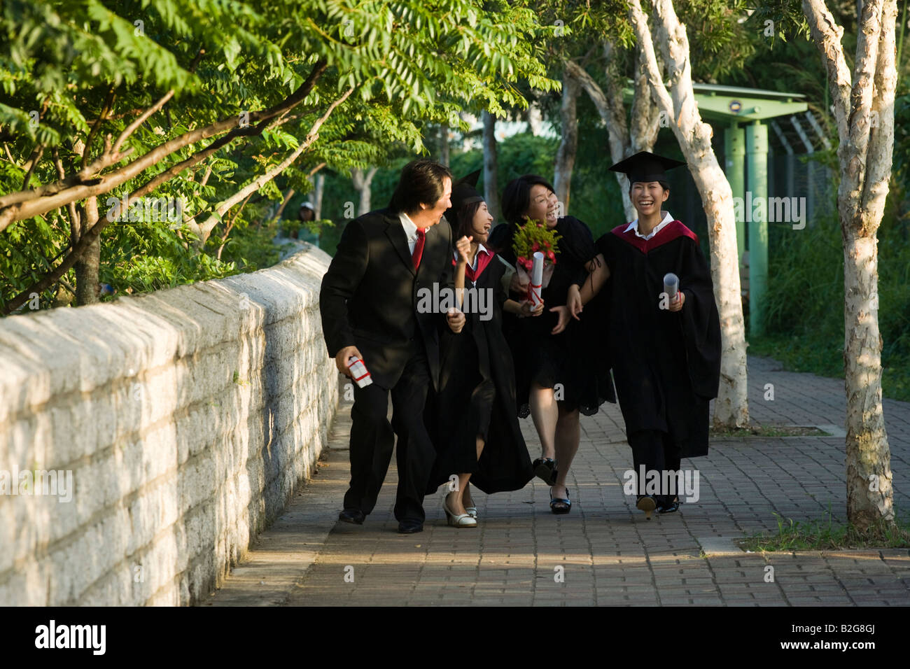Two female graduates walking with their parents and smiling Stock Photo ...