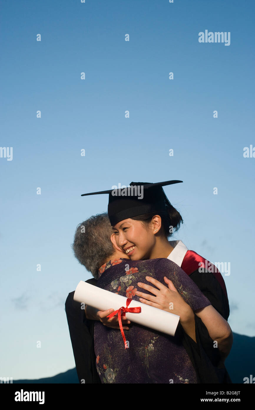 Rear view of a senior woman hugging a young female graduate Stock Photo ...