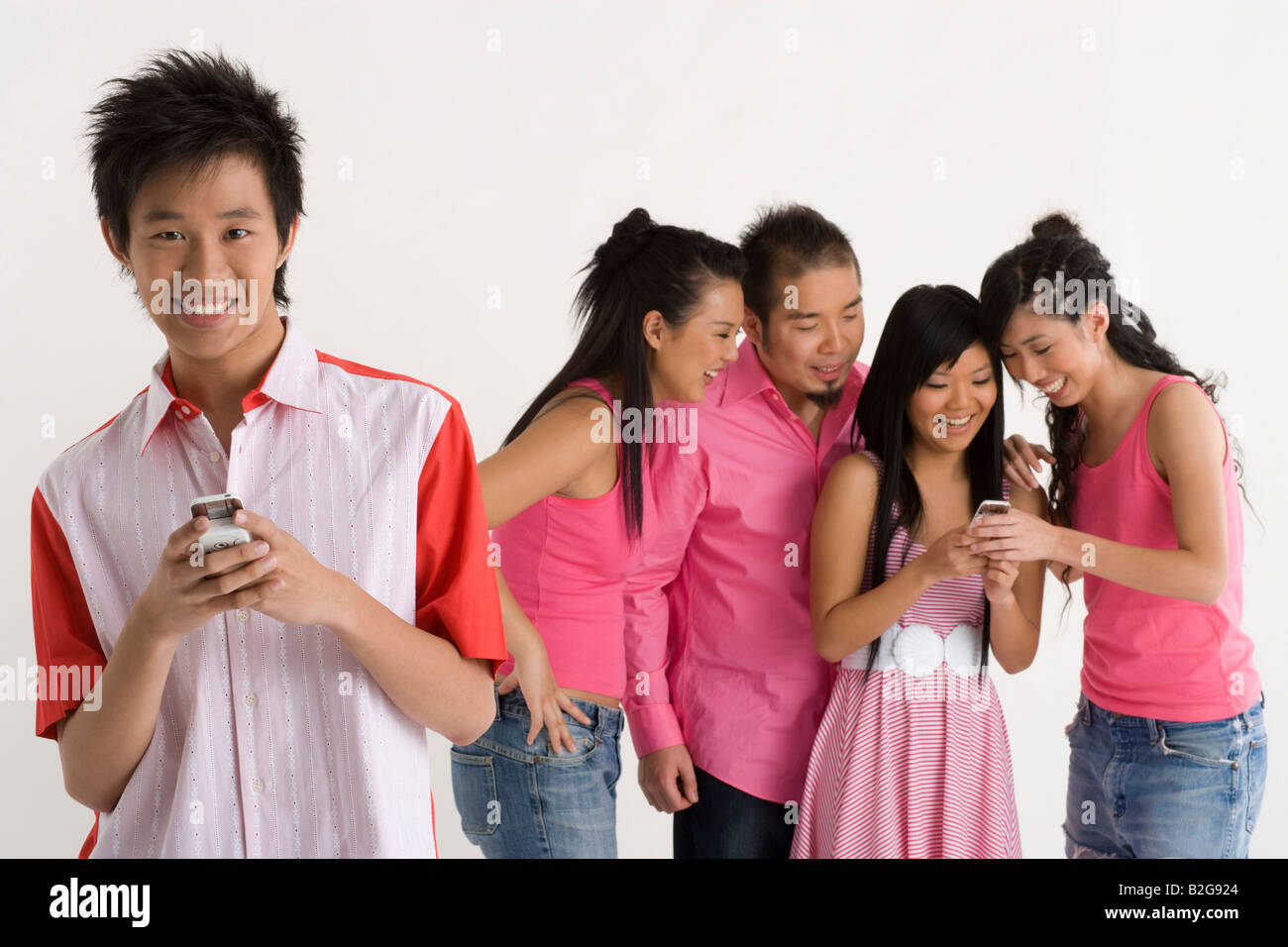 Portrait of a young man text messaging and his friends in the ...