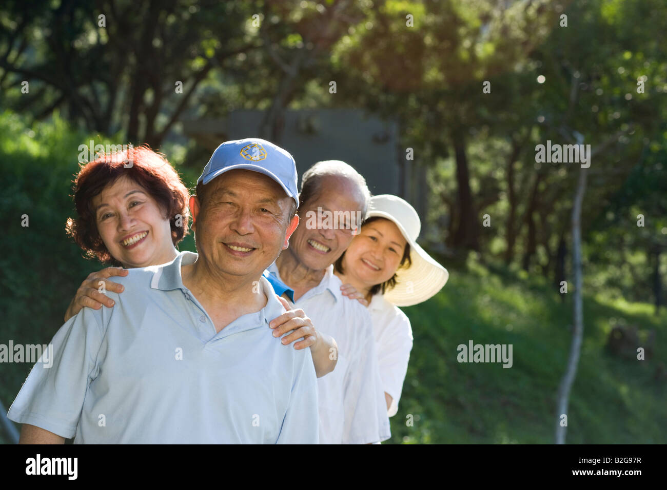 Portrait of two couples smiling in a row in a park Stock Photo - Alamy