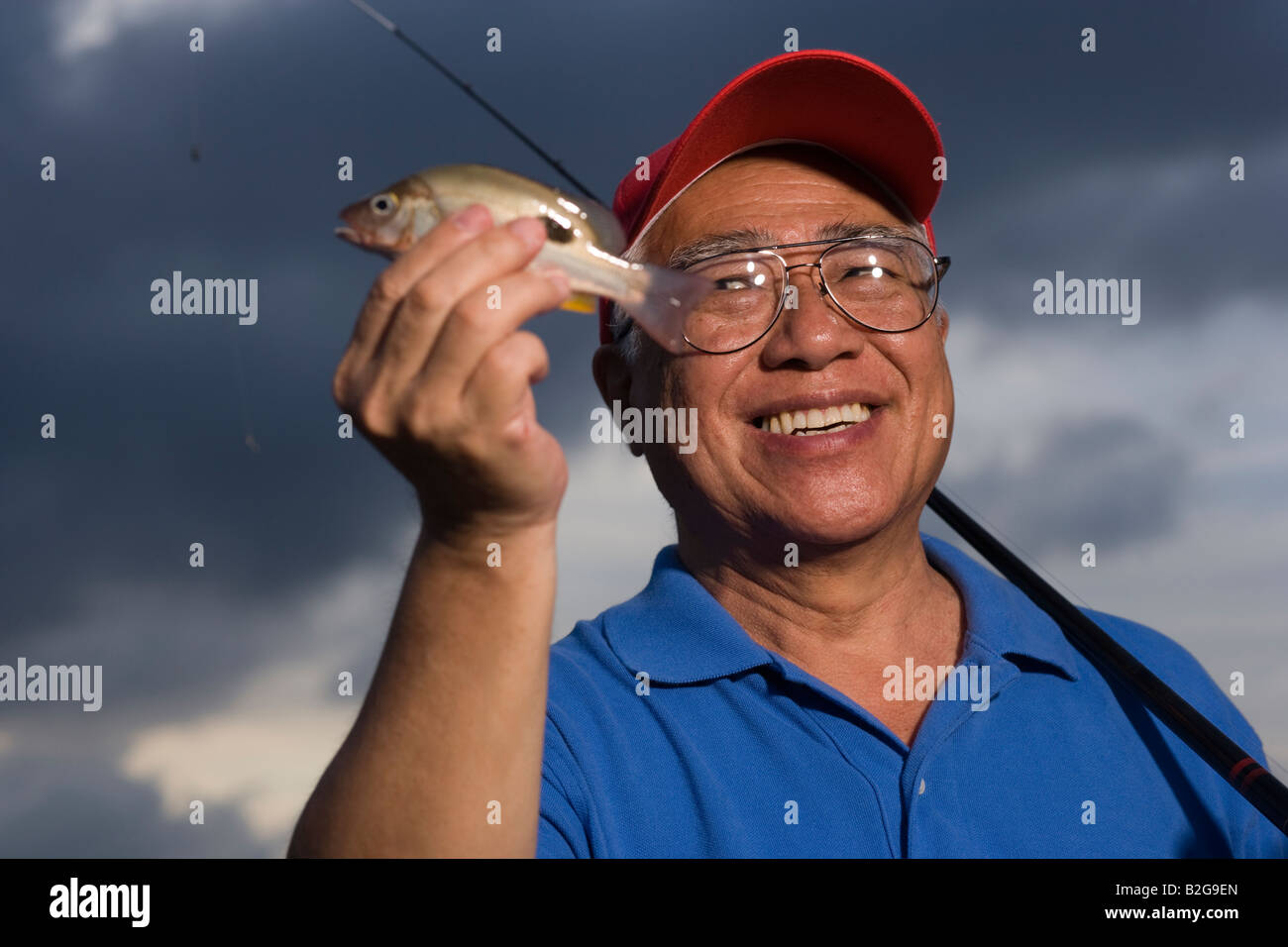 Close-up of a senior man holding a fish and smiling Stock Photo - Alamy