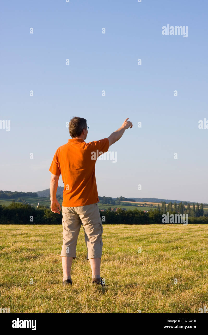 Man pointing with his outstretched arm on a meadow Stock Photo - Alamy