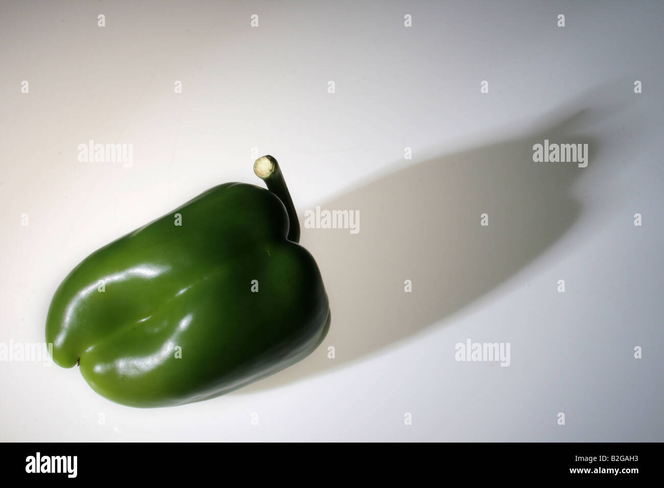 Green pepper on white background, ambiguously shaped, casting a shadow ...