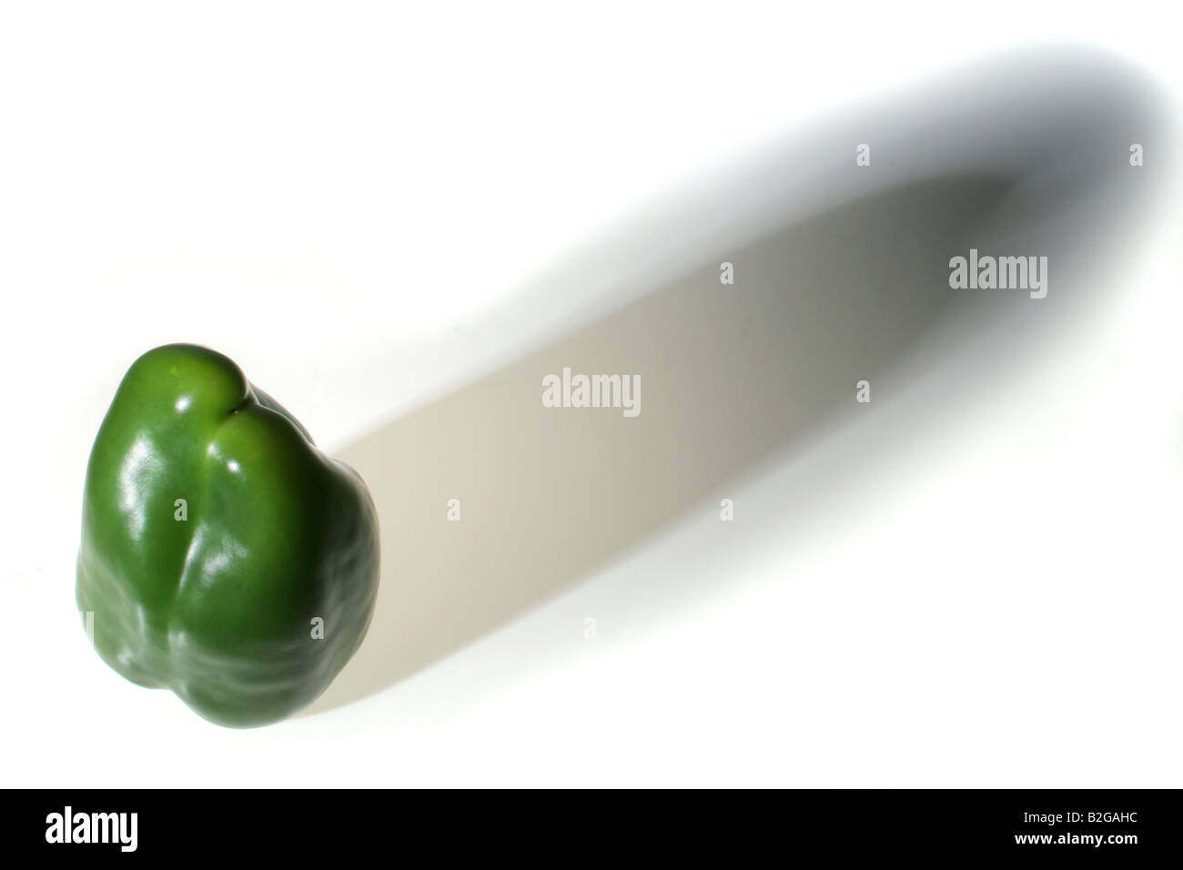 Green pepper on white background, ambiguously shaped, casting a shadow ...