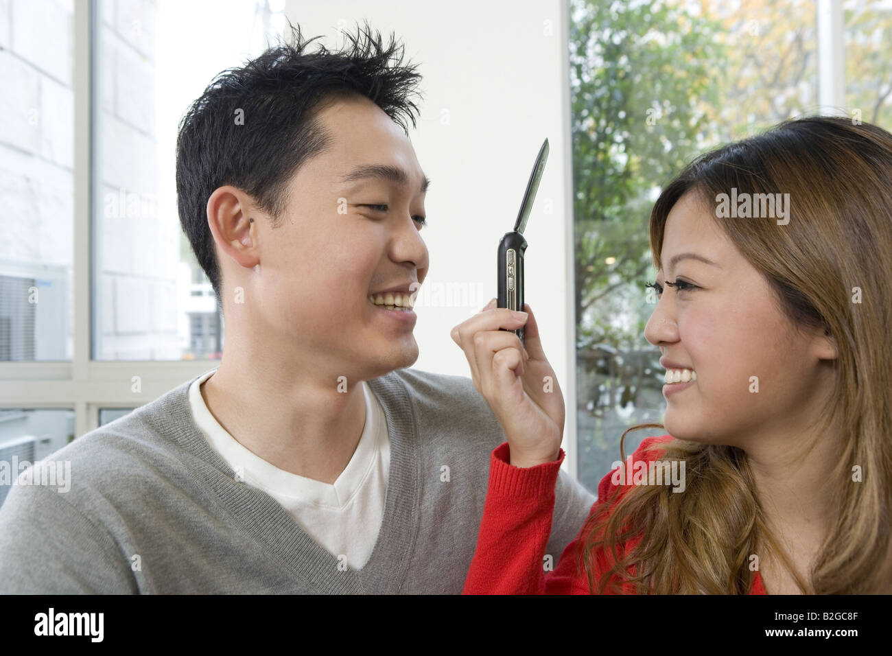 A young woman clicking photograph of her boyfriend Stock Photo - Alamy