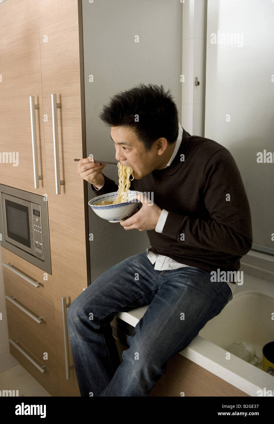 View of a young man eating noodles Stock Photo - Alamy