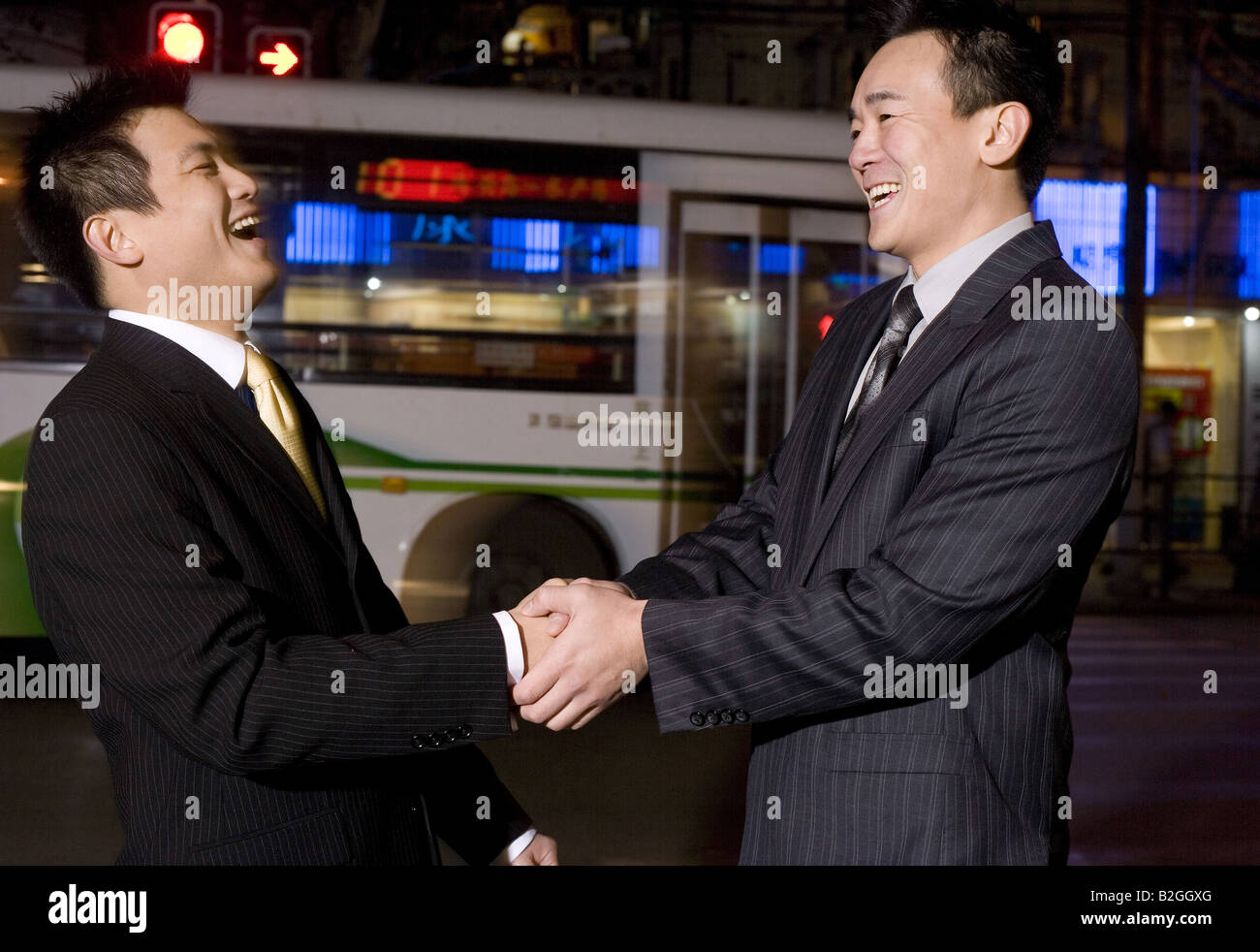 View of businessmen laughing while shaking hands Stock Photo - Alamy