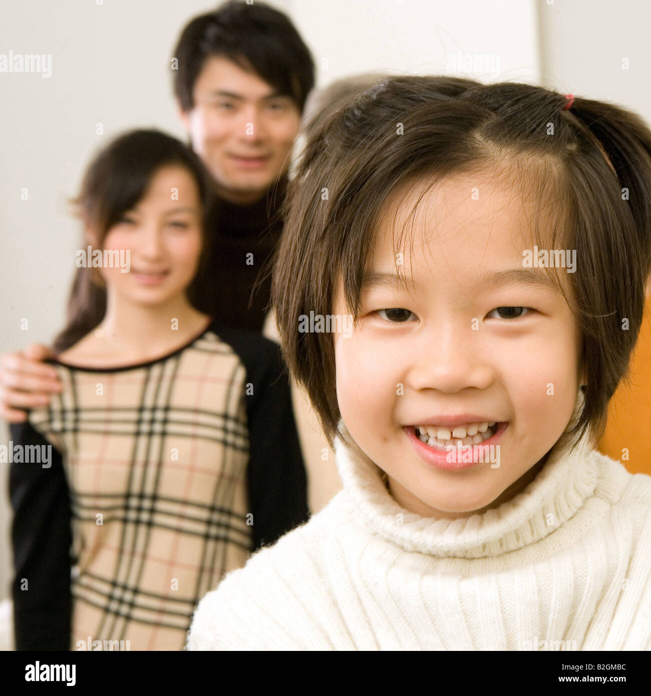Portrait of a girl standing with her parents and smiling Stock Photo ...