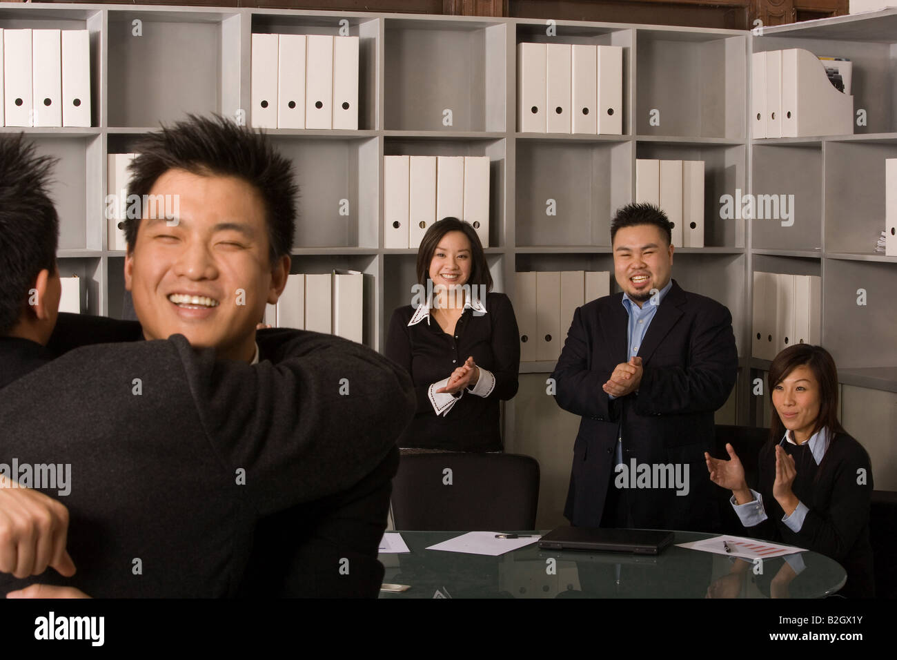 Close-up of two businessmen hugging each other with their colleagues ...