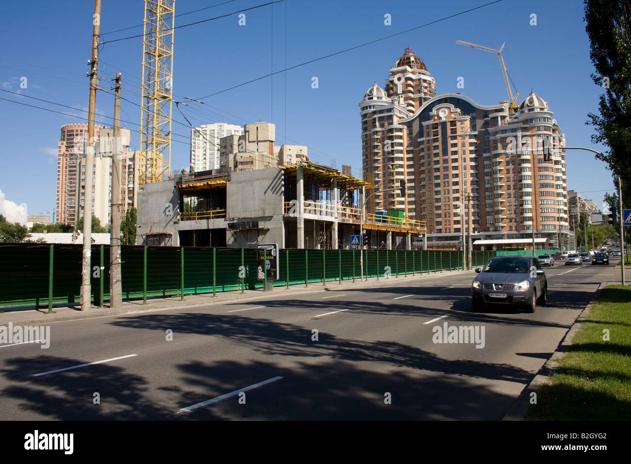 Construction site with high-rise buildings, green fence, cranes, and a ...