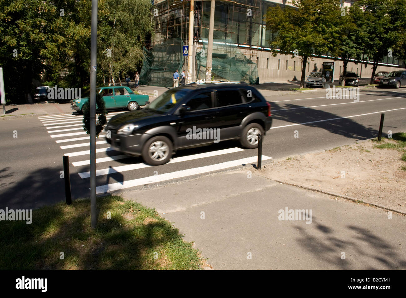 A black car driving over a pedestrian crosswalk on a sunny day in Kyiv ...