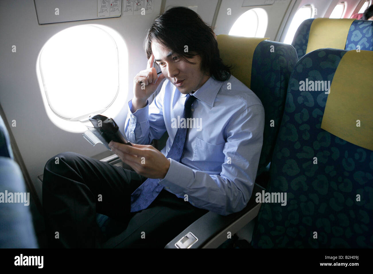 Businessman using a personal data assistant in an airplane Stock Photo ...