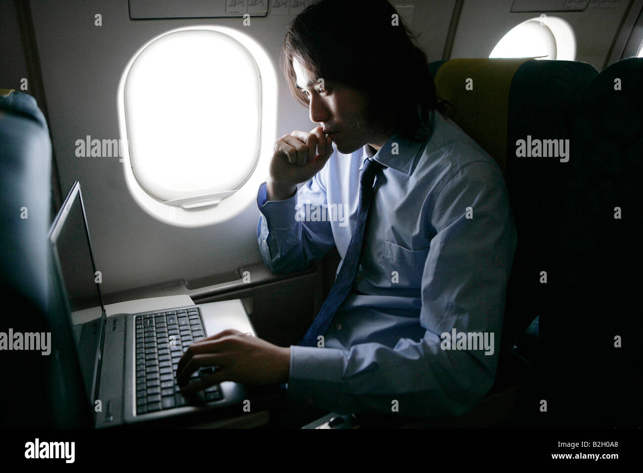 Businessman using a laptop in an airplane Stock Photo - Alamy