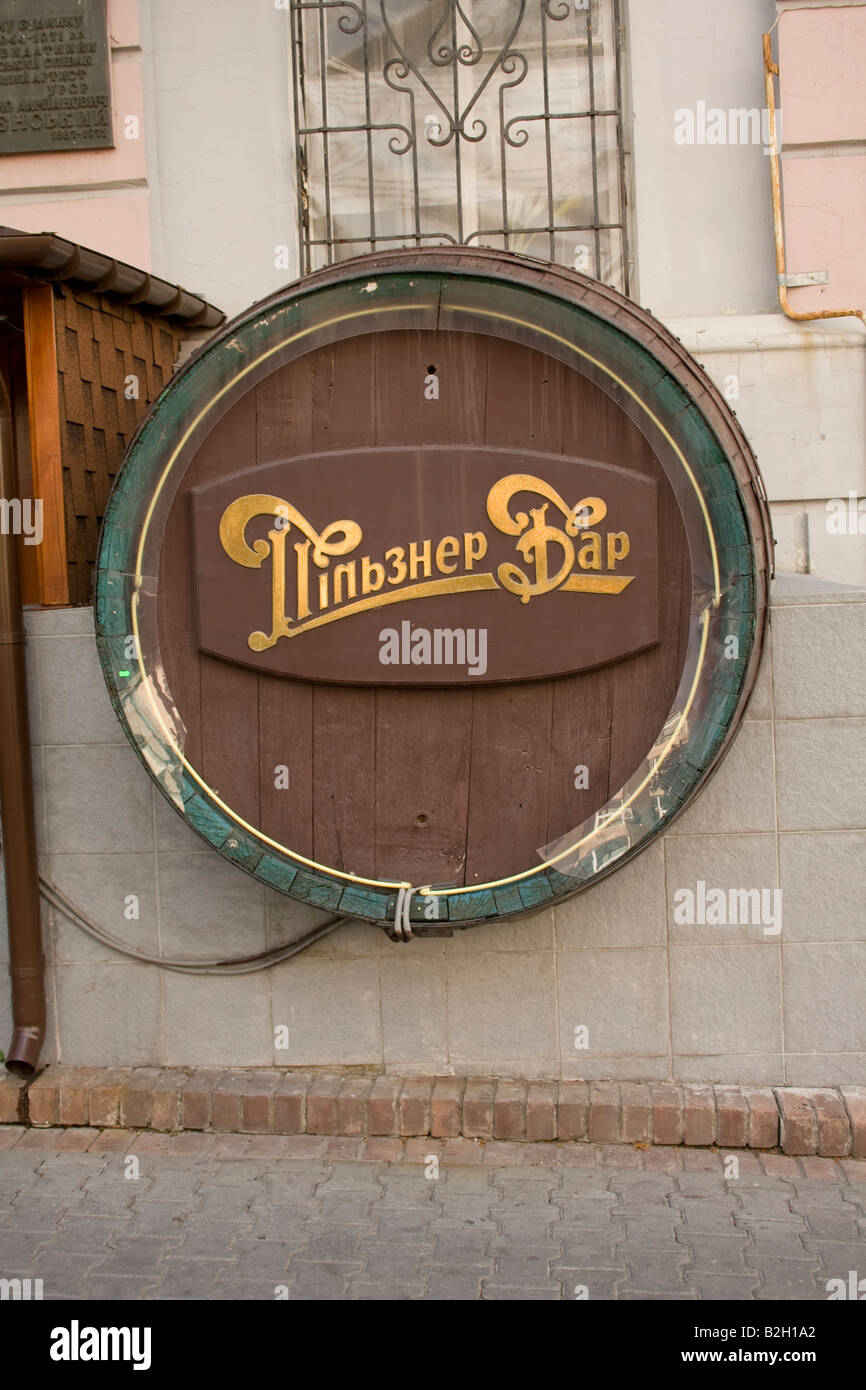 A wooden barrel sign with "Pilsner Bar" in golden lettering mounted on ...