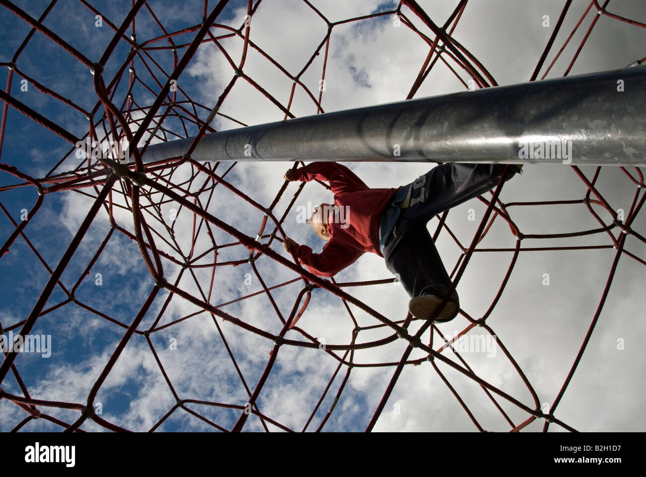 Stock photo of a young boy climbing on a rope climbing frame Stock ...