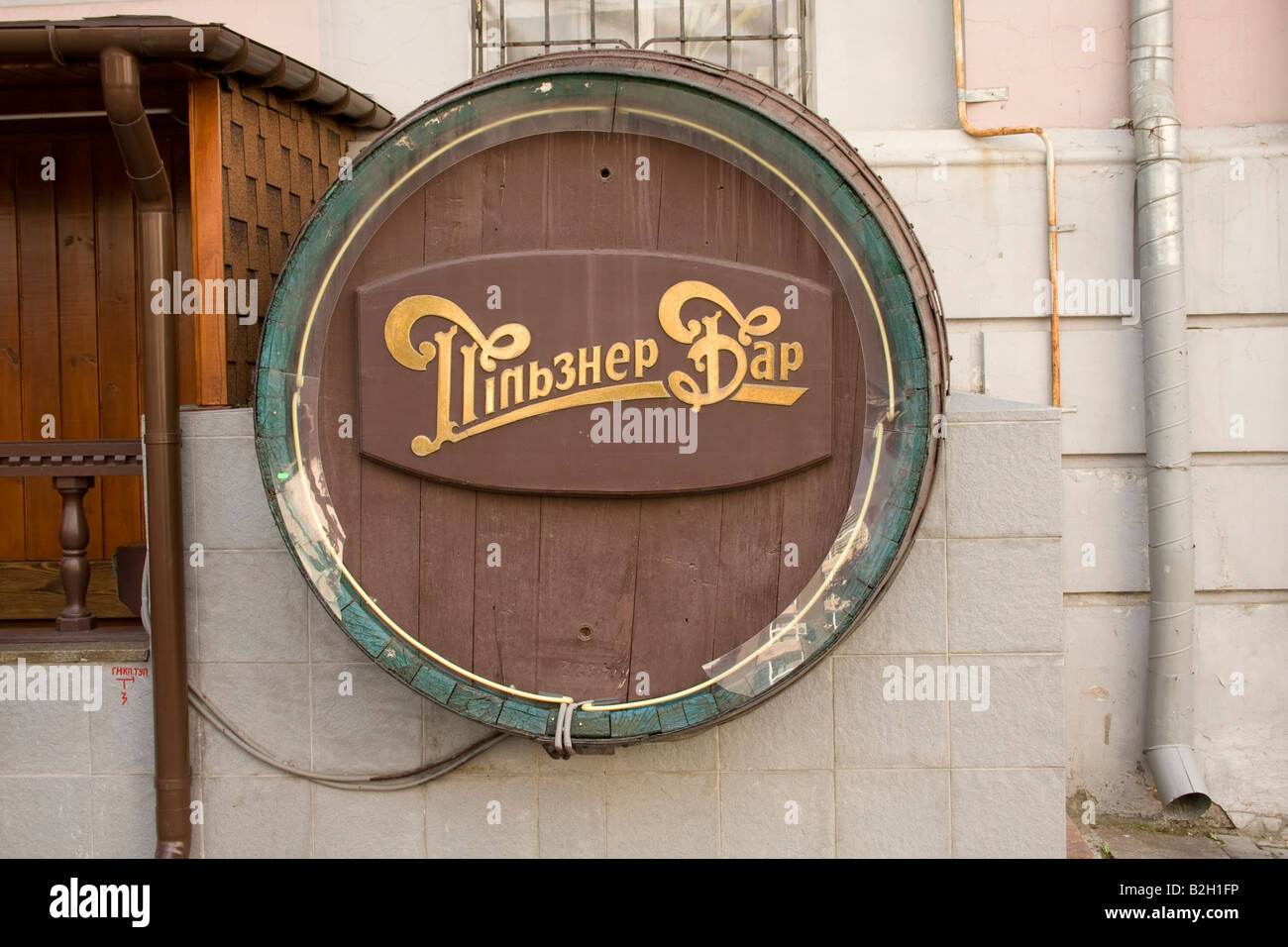 A wooden barrel sign with "Pilsner Bar" in golden lettering mounted on ...