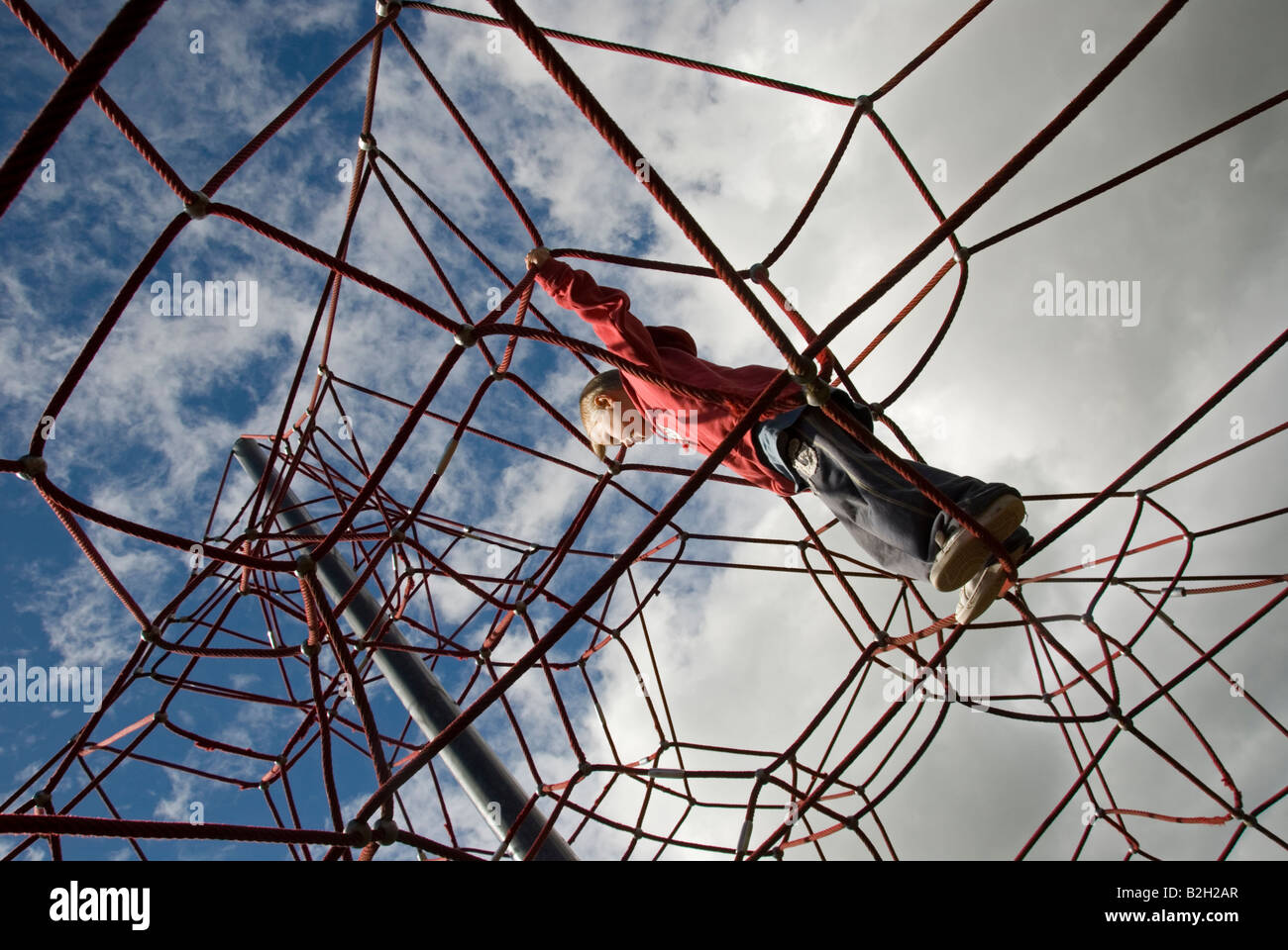 Stock photo of a young boy climbing on a rope climbing frame Stock ...