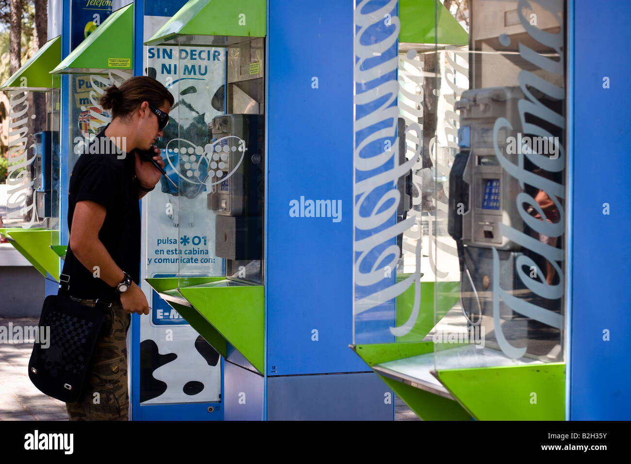 Young man makes phone call in public telephone box of the spanish ...