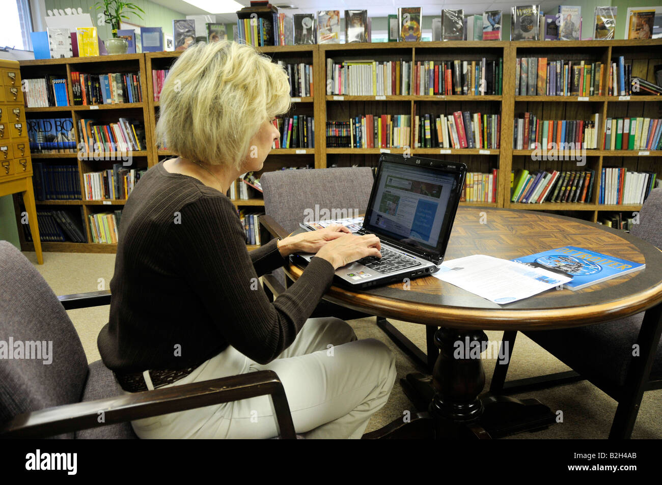 Female working on a laptop computer at a public library Stock Photo - Alamy