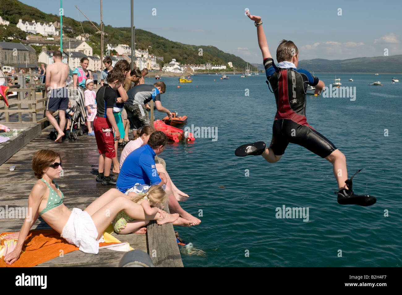 Teenager leaping off the jetty in Aberdyfi into the Dyfi Estuary summer ...