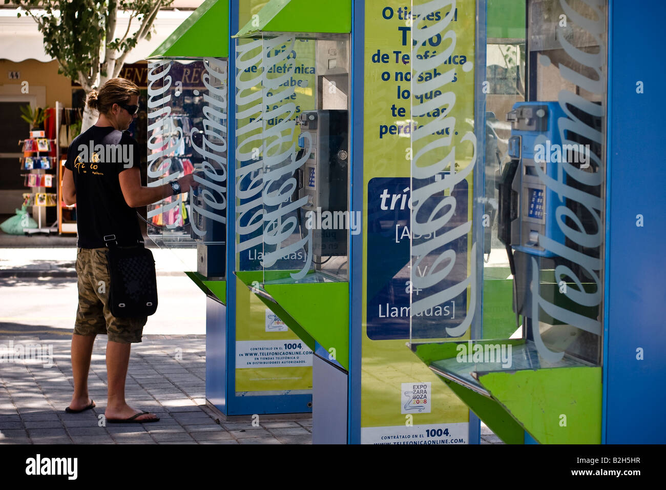 Young man makes phone call in public telephone box of the spanish ...