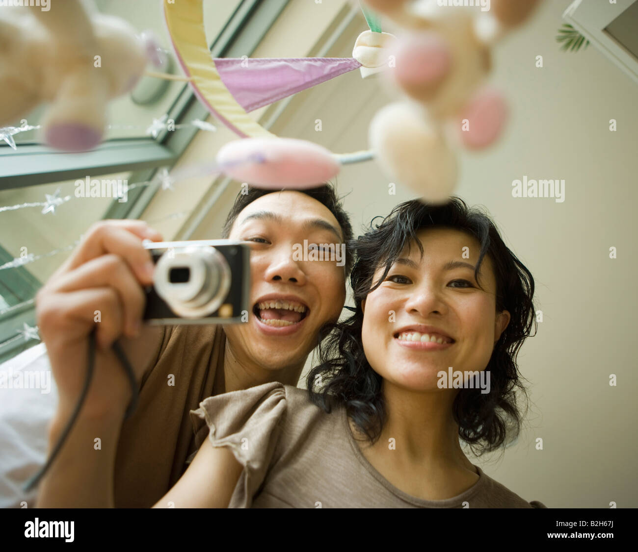 Low angle view of mid adult couple smiling and holding a digital camera ...
