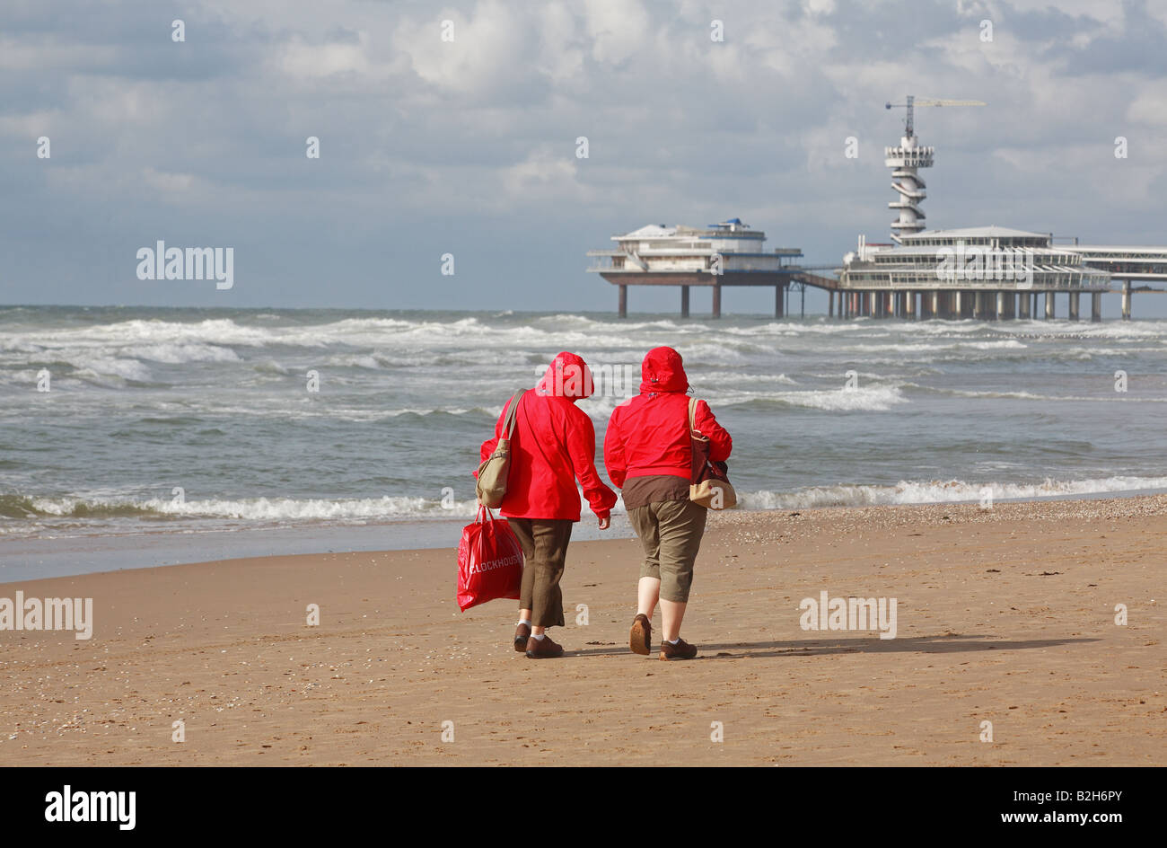 Two ladies in red coats at Scheveningen beach on a windy day, the ...