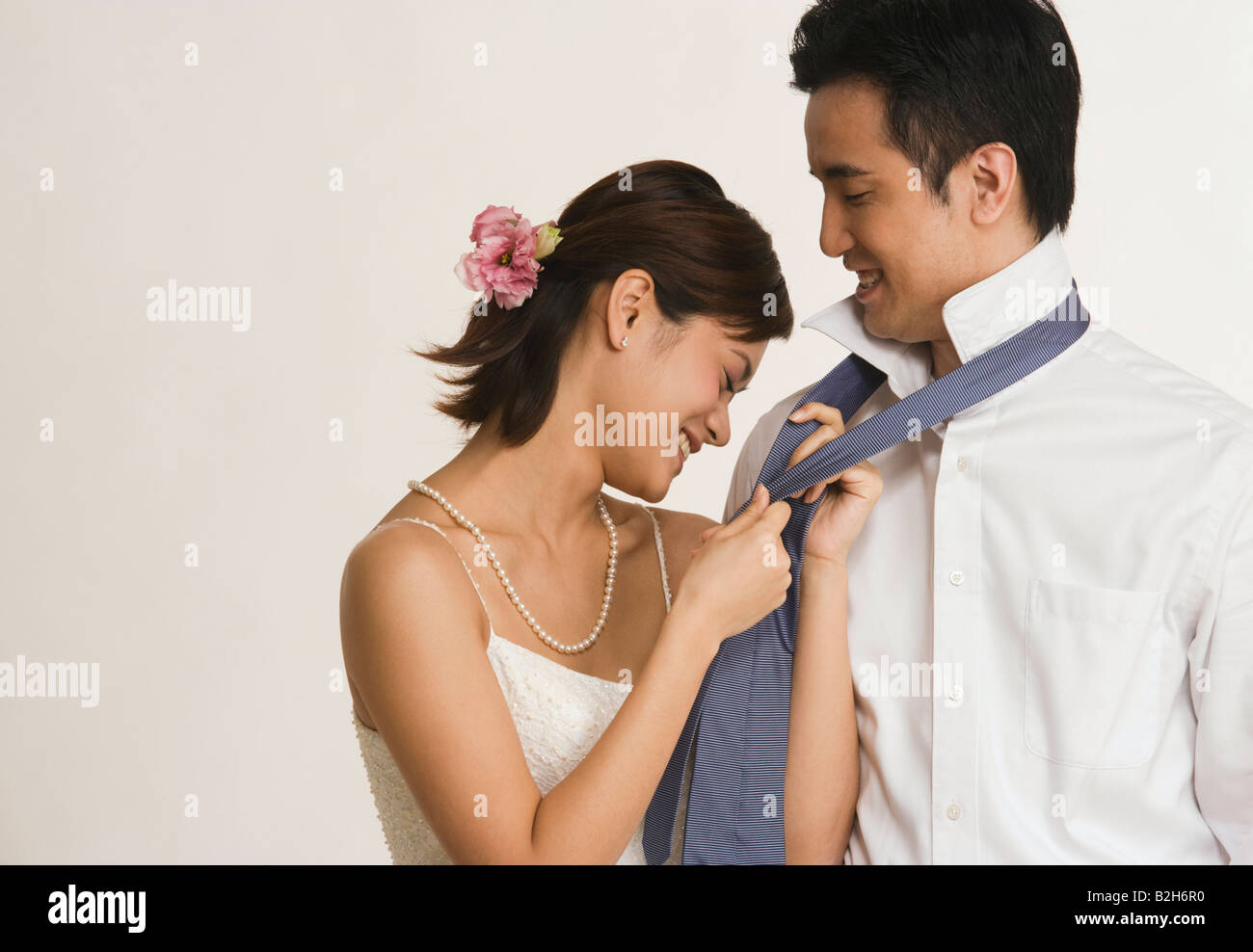 Close-up of a bride tying her groom's tie and smiling Stock Photo - Alamy