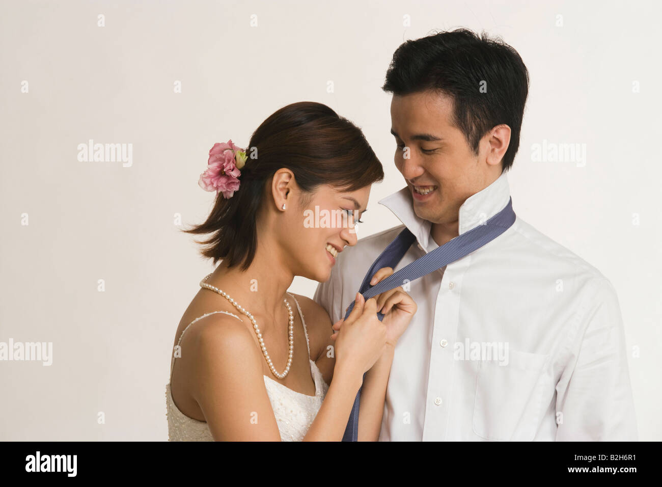 Close-up of a bride tying her groom's tie and smiling Stock Photo - Alamy