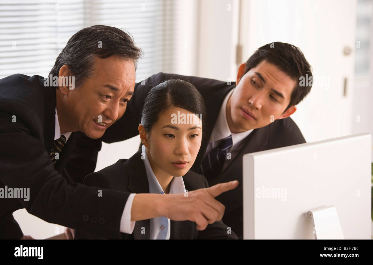 Three business executives looking at a computer monitor Stock Photo - Alamy