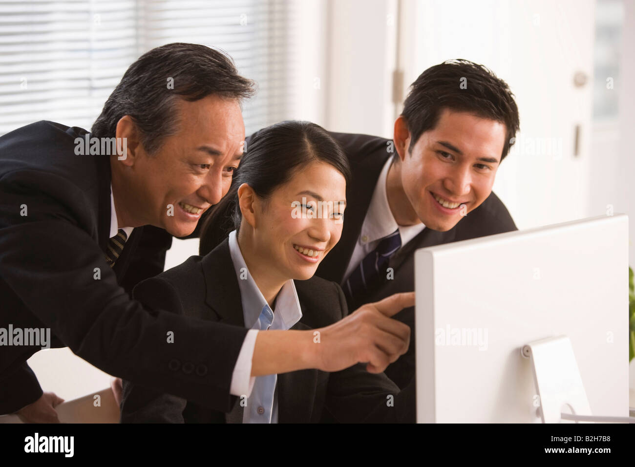 Three business executives looking at a computer monitor Stock Photo - Alamy