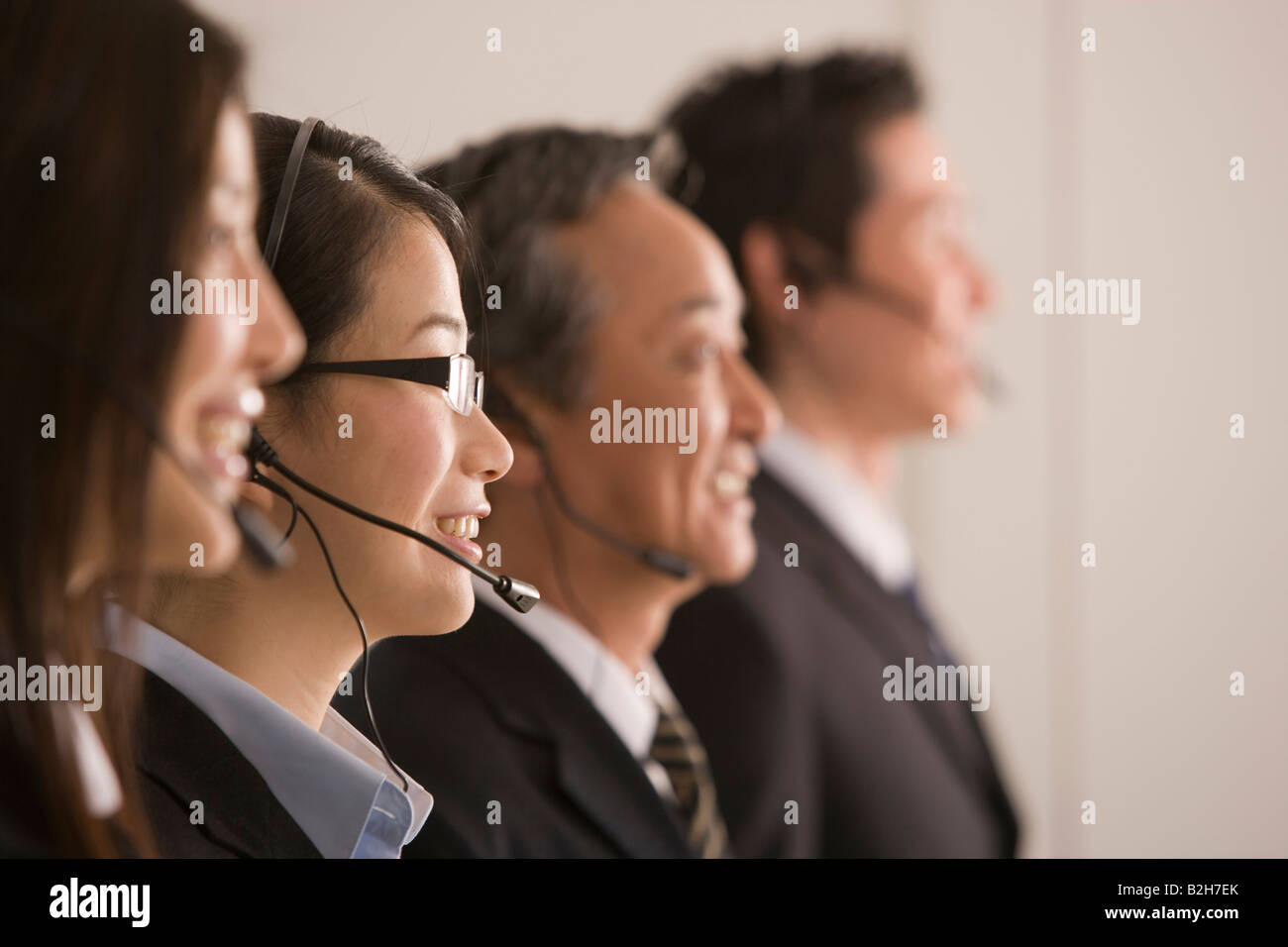 Four business executives wearing headsets Stock Photo - Alamy