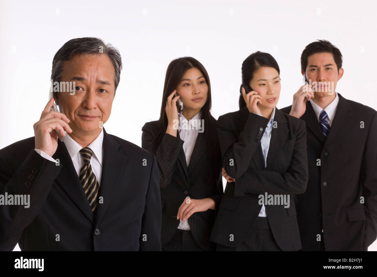 Four business executives using their mobile phones Stock Photo - Alamy