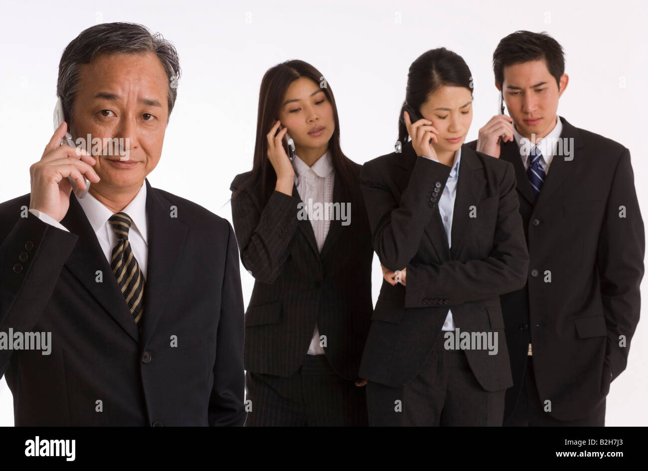 Four business executives using their mobile phones Stock Photo - Alamy